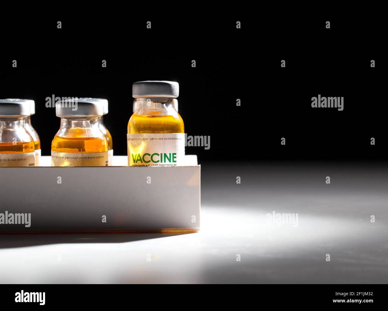 Vials with coronavirus vaccine in packaging on a black background and ...