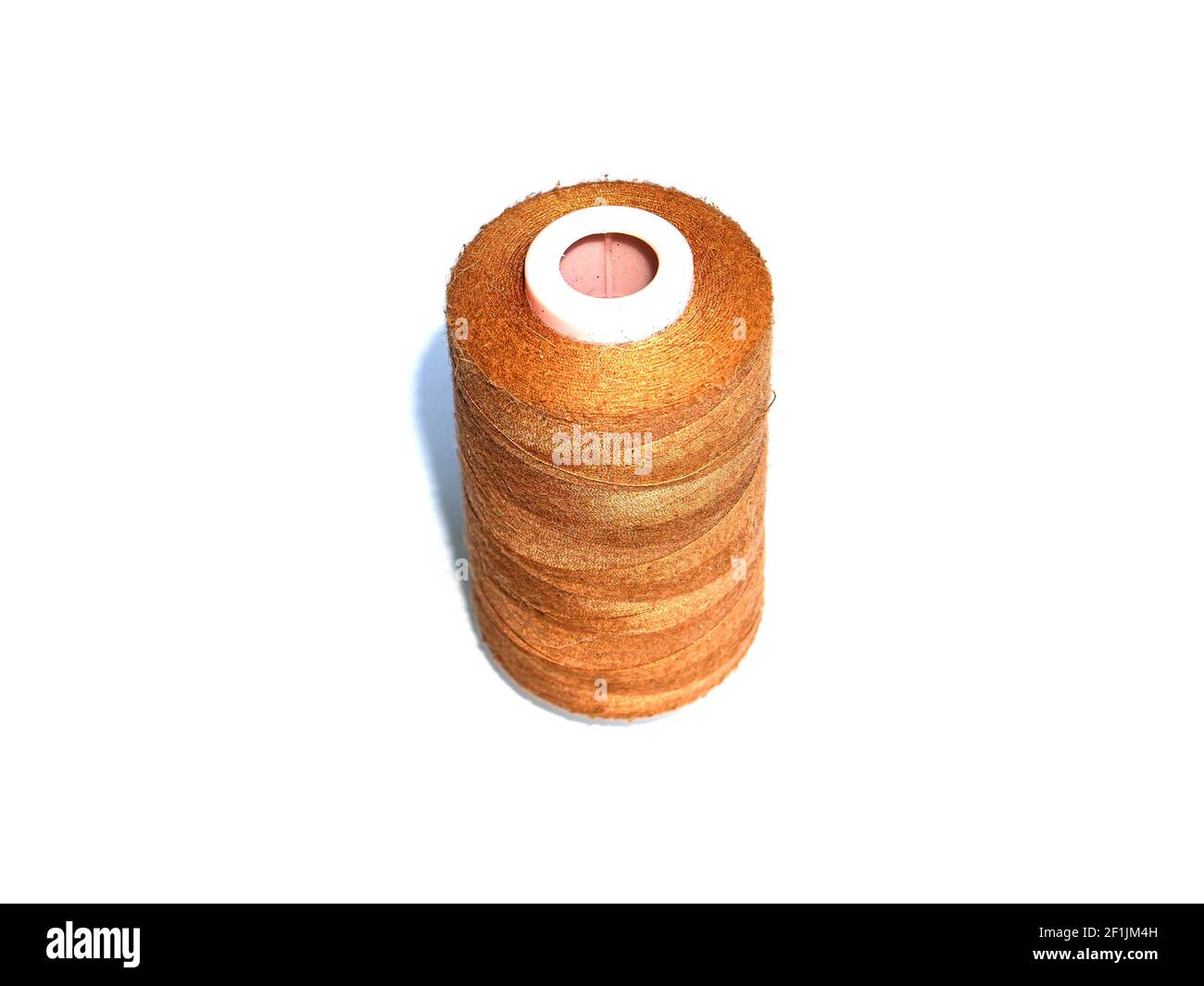 A large spool of brown sewing thread on a white background. Spool of ...