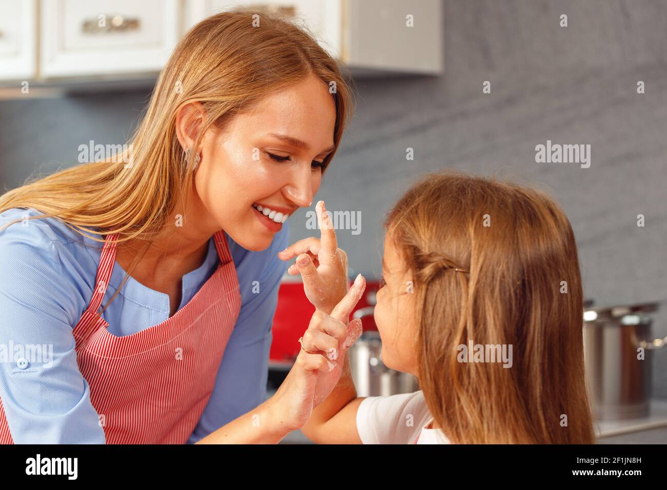 Little girl and her mother stain each other noses with flour Stock ...