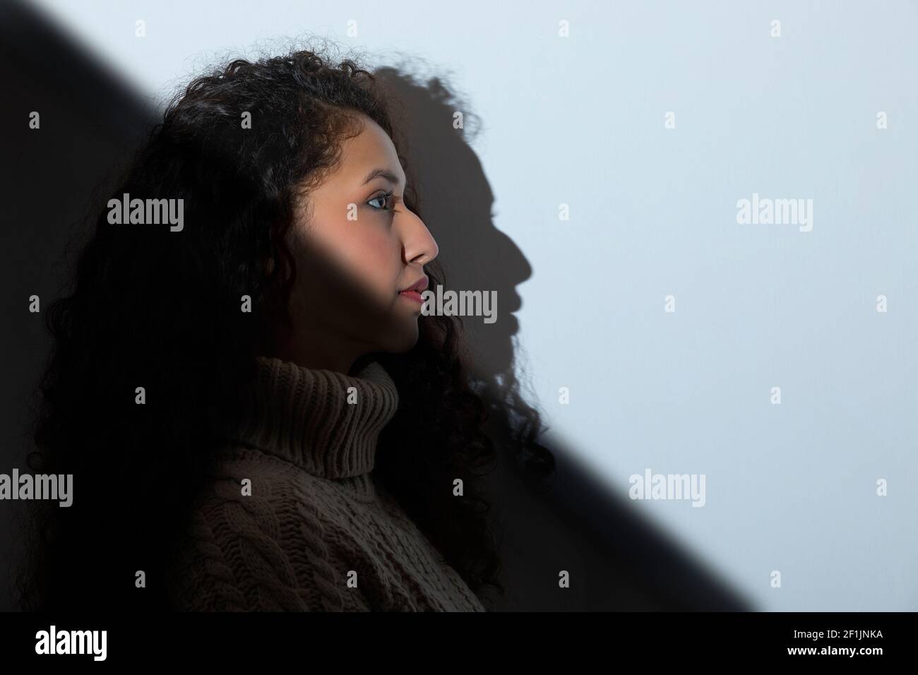 SIDE SHOT OF A TEENAGE GIRL WITH LIGHT PARTIALLY FALLING ON HER FACE ...