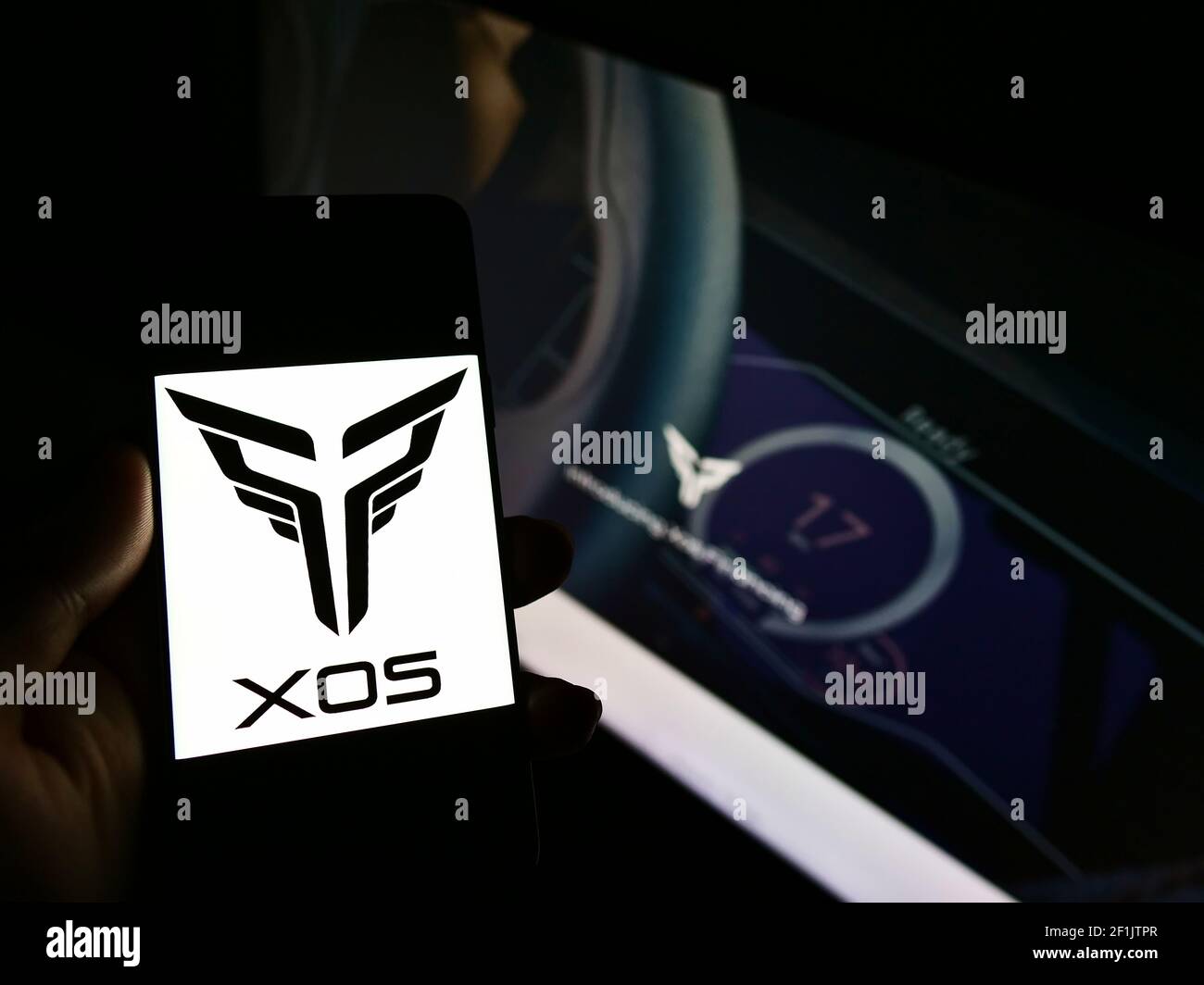Person holding smartphone with logo of US electric vehicle company Xos ...