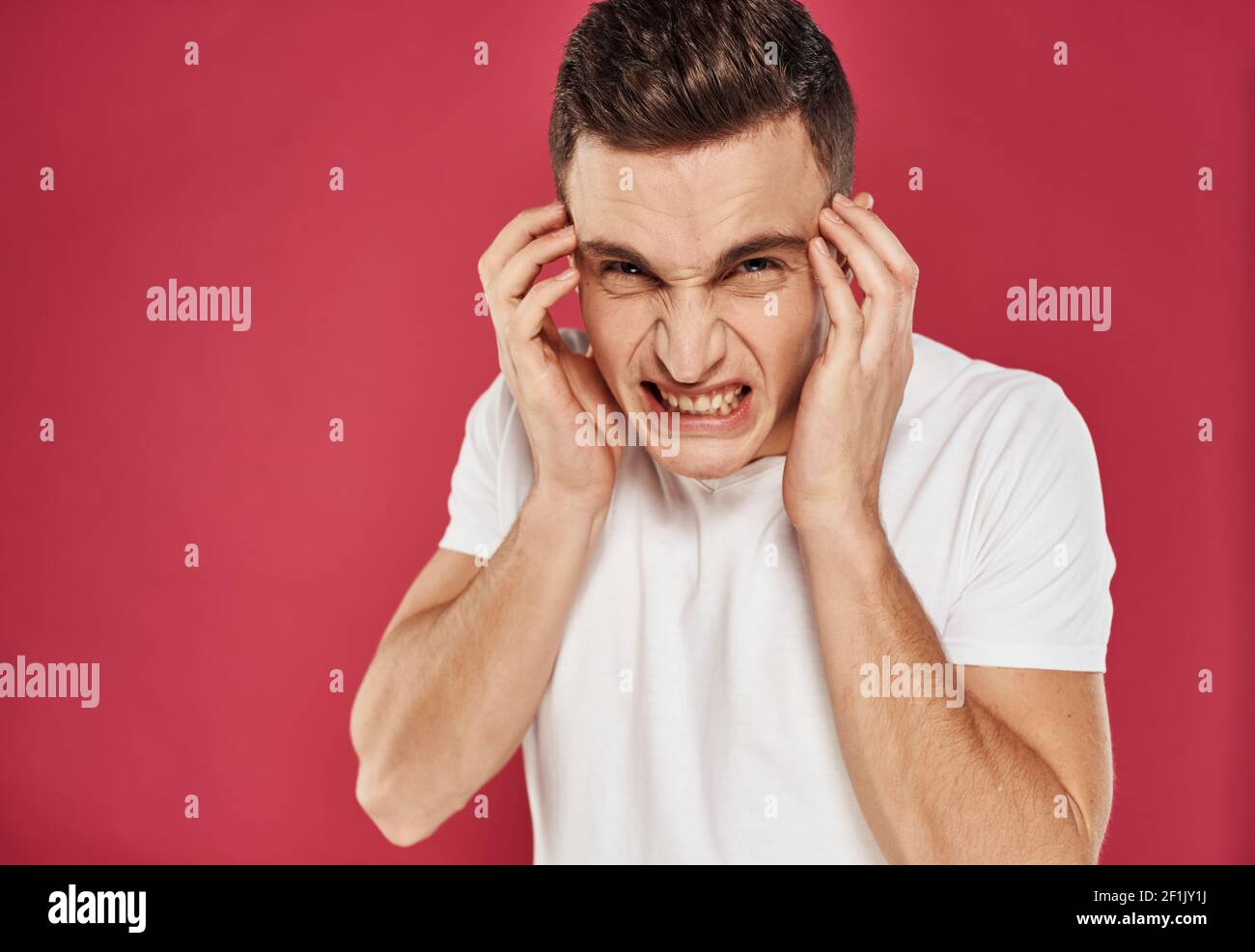 Man with displeased facial expression emotions white t-shirt studio red ...