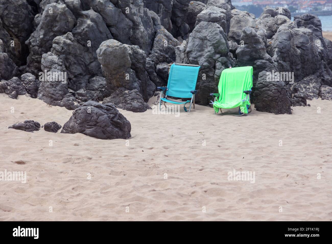 Lounge chairs in front of a rock on the beach Stock Photo - Alamy