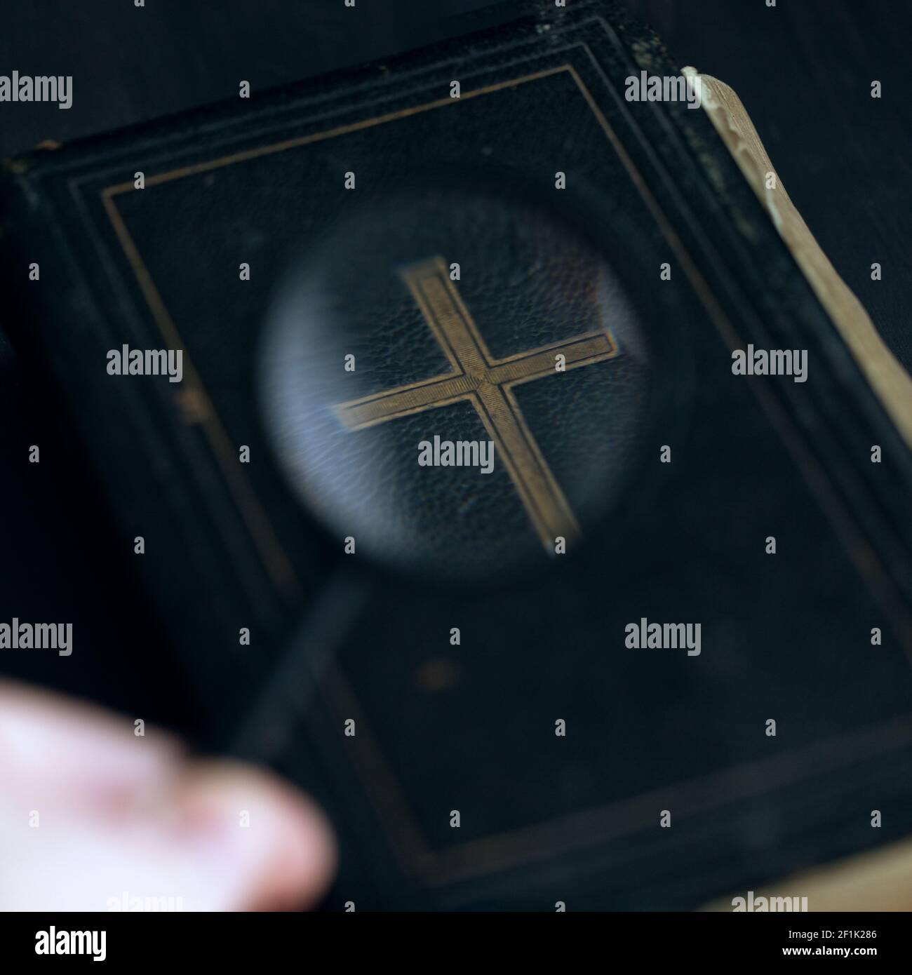 Vintage antique Bible book on table and magnifying glass in human hand ...