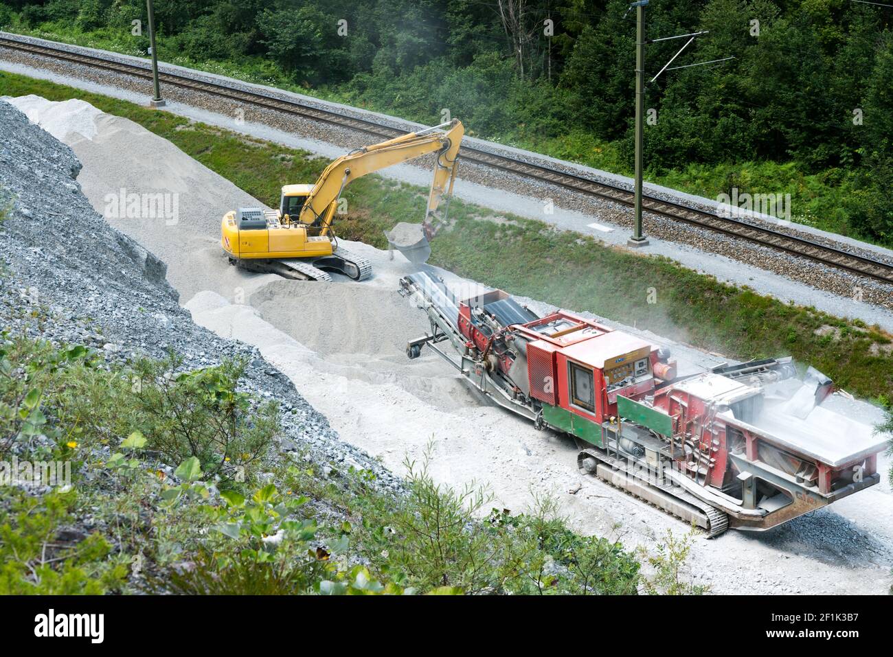 Excavator and rock grinder working to produce fine ground pebbles from ...