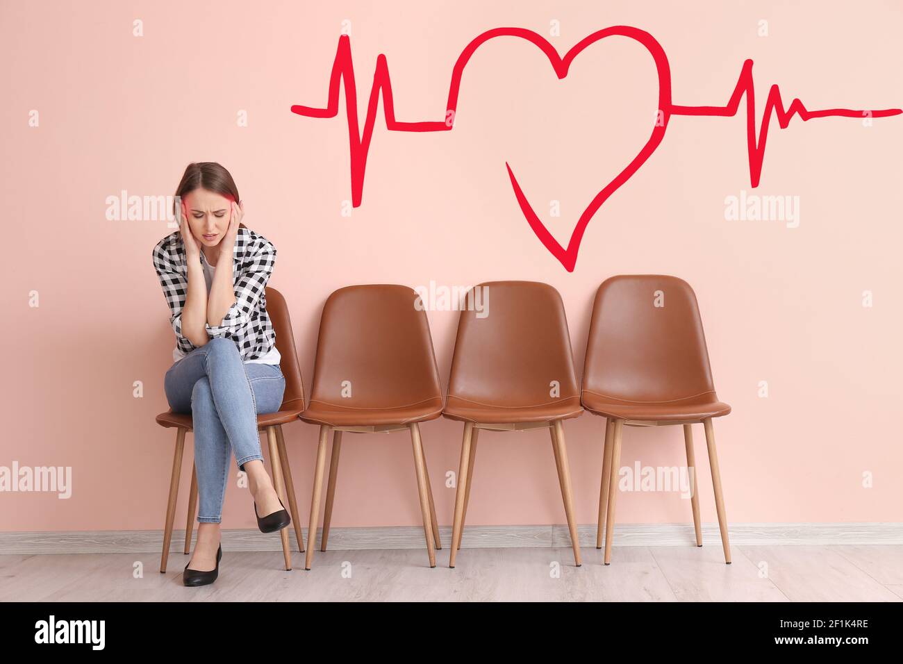 Waiting young woman sitting on chair near color wall Stock Photo - Alamy
