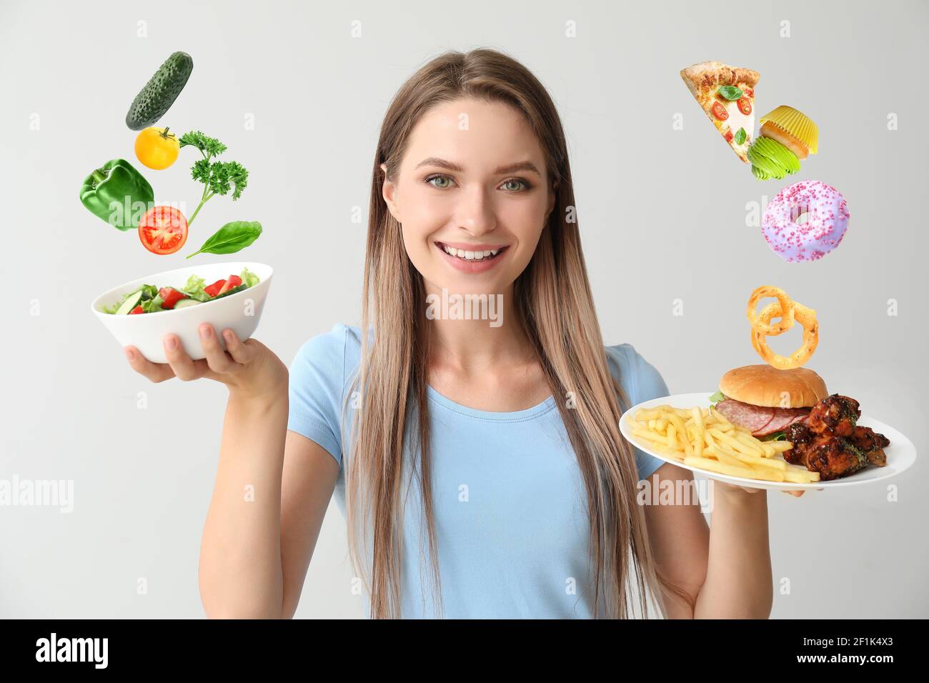 Young woman with healthy and unhealthy food on light background. Diet ...