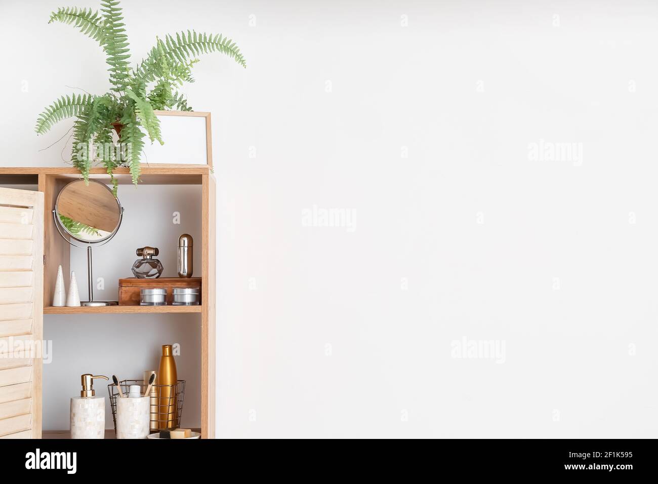 Stylish shelf unit with bath accessories near light wall Stock Photo ...