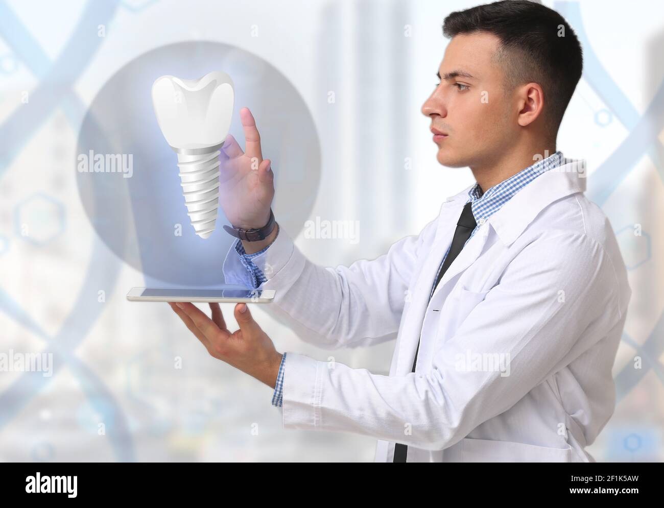 Male dentist with tablet computer and digital model of tooth implant in ...