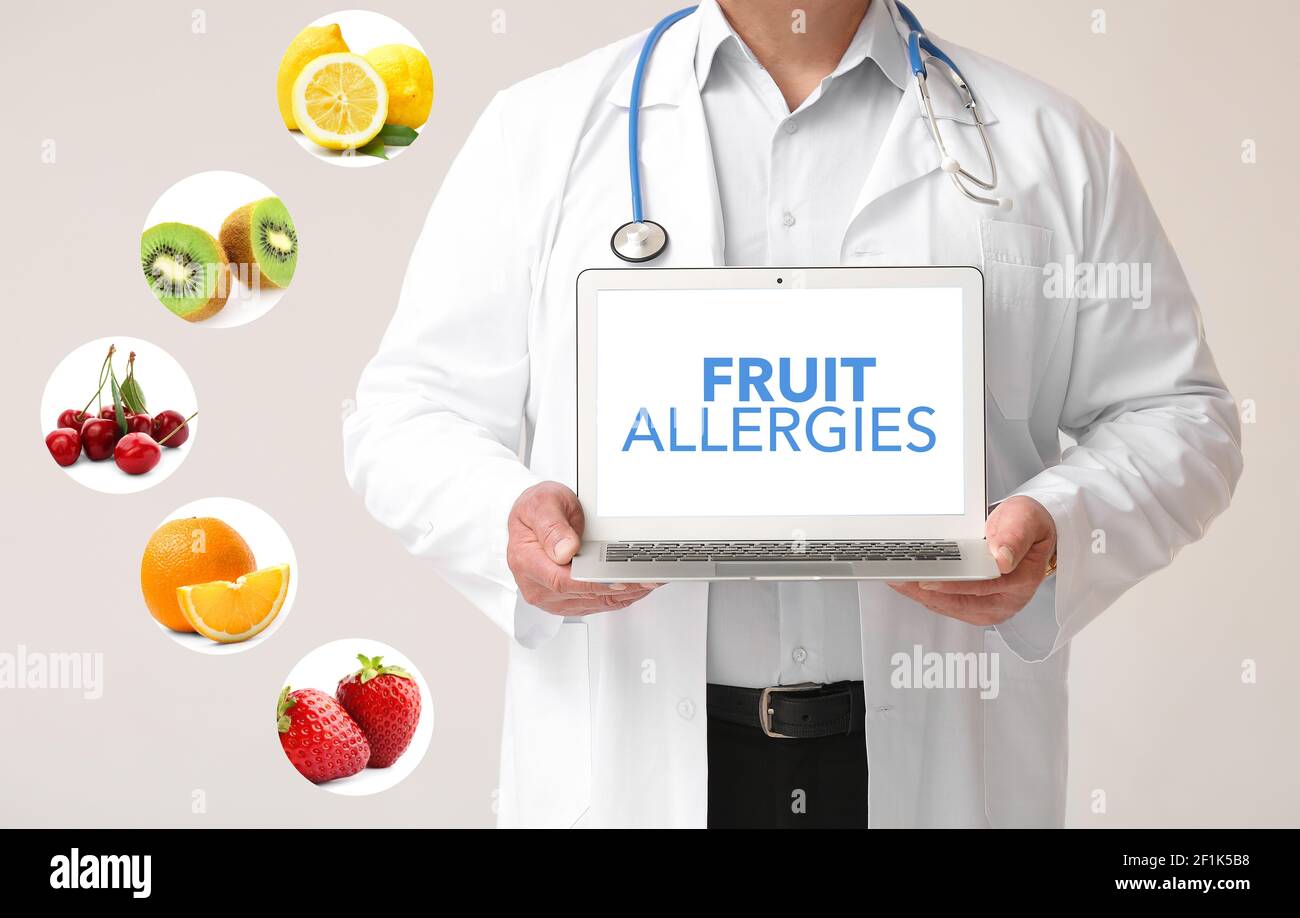 Male doctor holding laptop and text "Fruit Allergies" on screen against ...