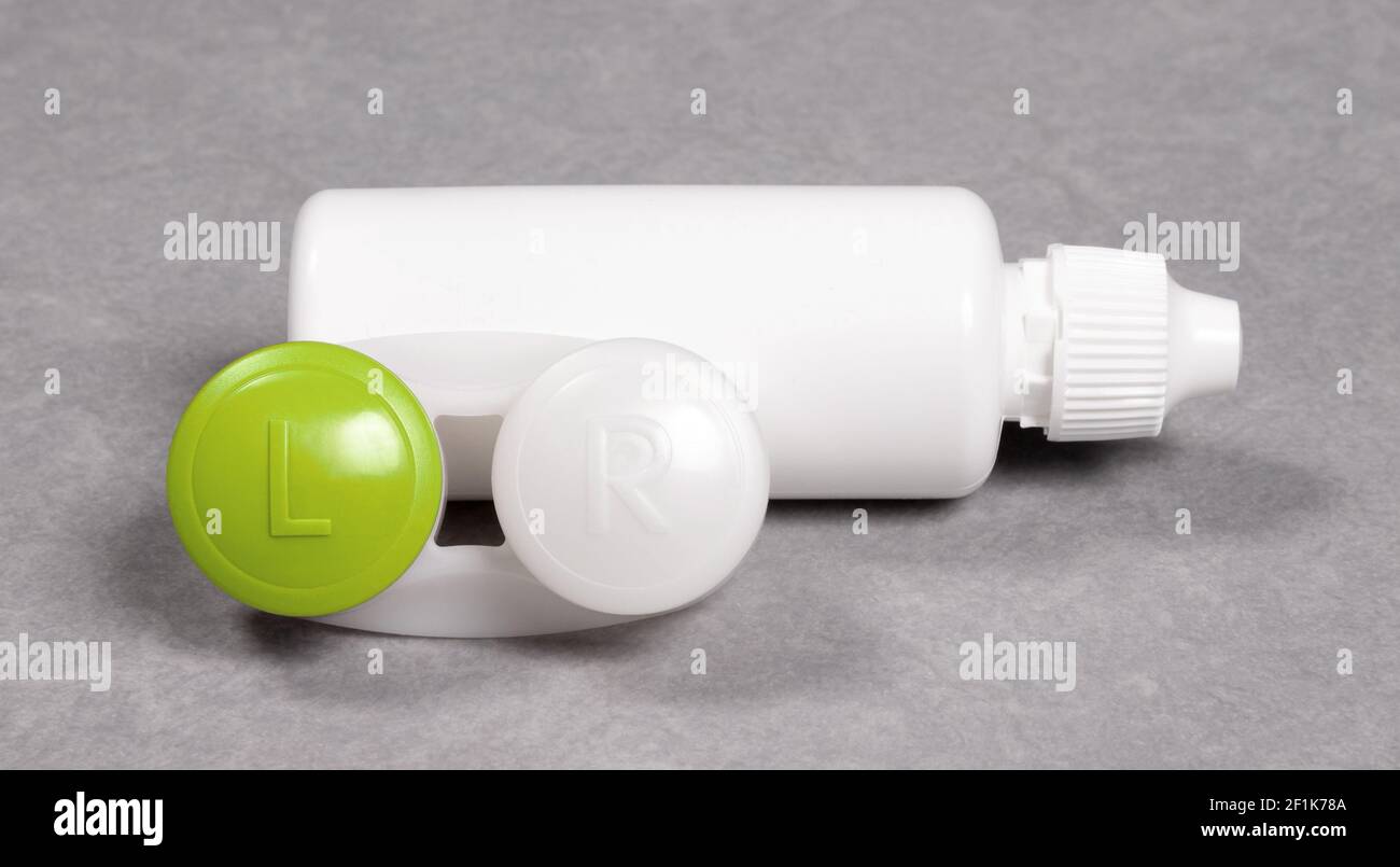 Green contact lens case and bottle of solution, isolated on grey ...