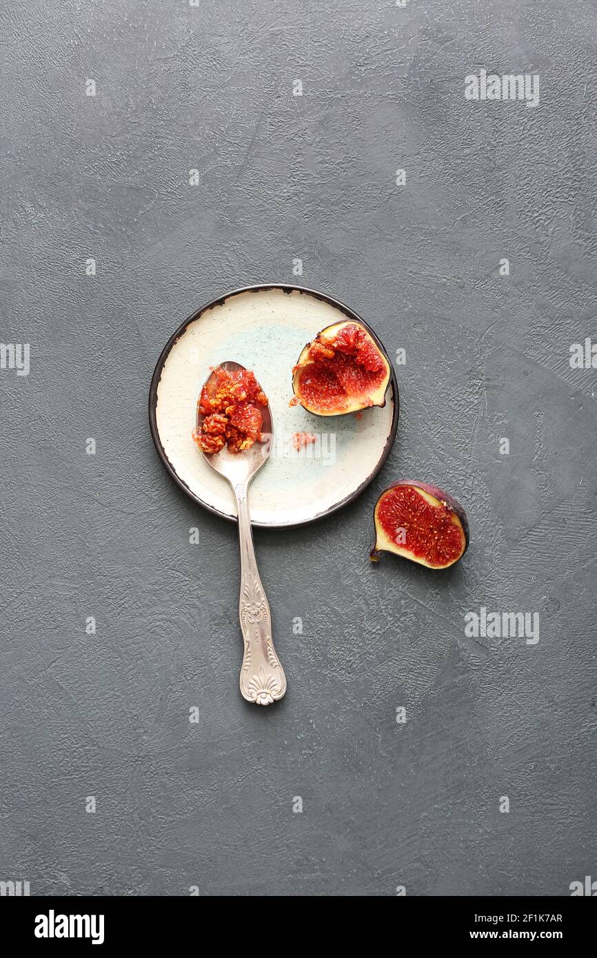 Spoon and cut fig on dark background Stock Photo - Alamy