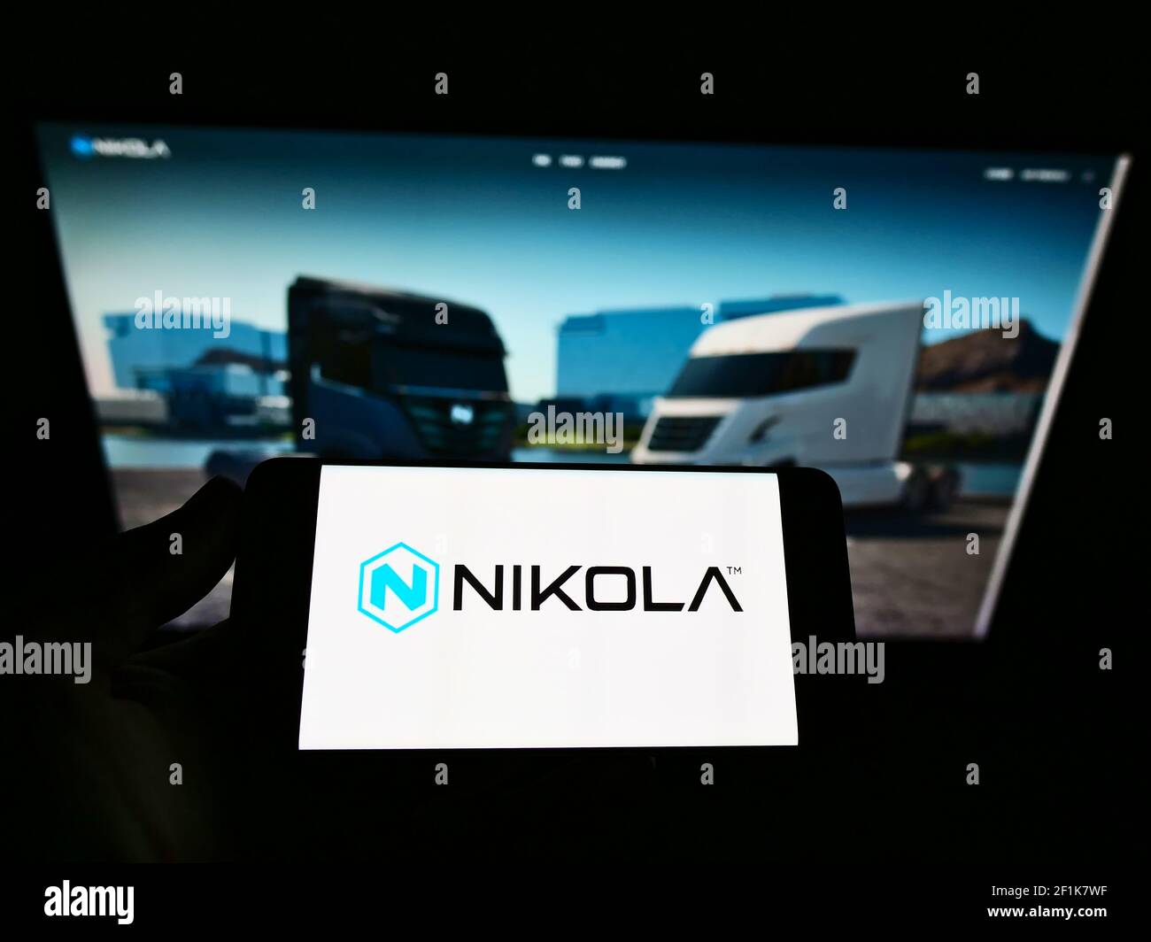 Person holding smartphone with logo of US zero-emission vehicle company ...