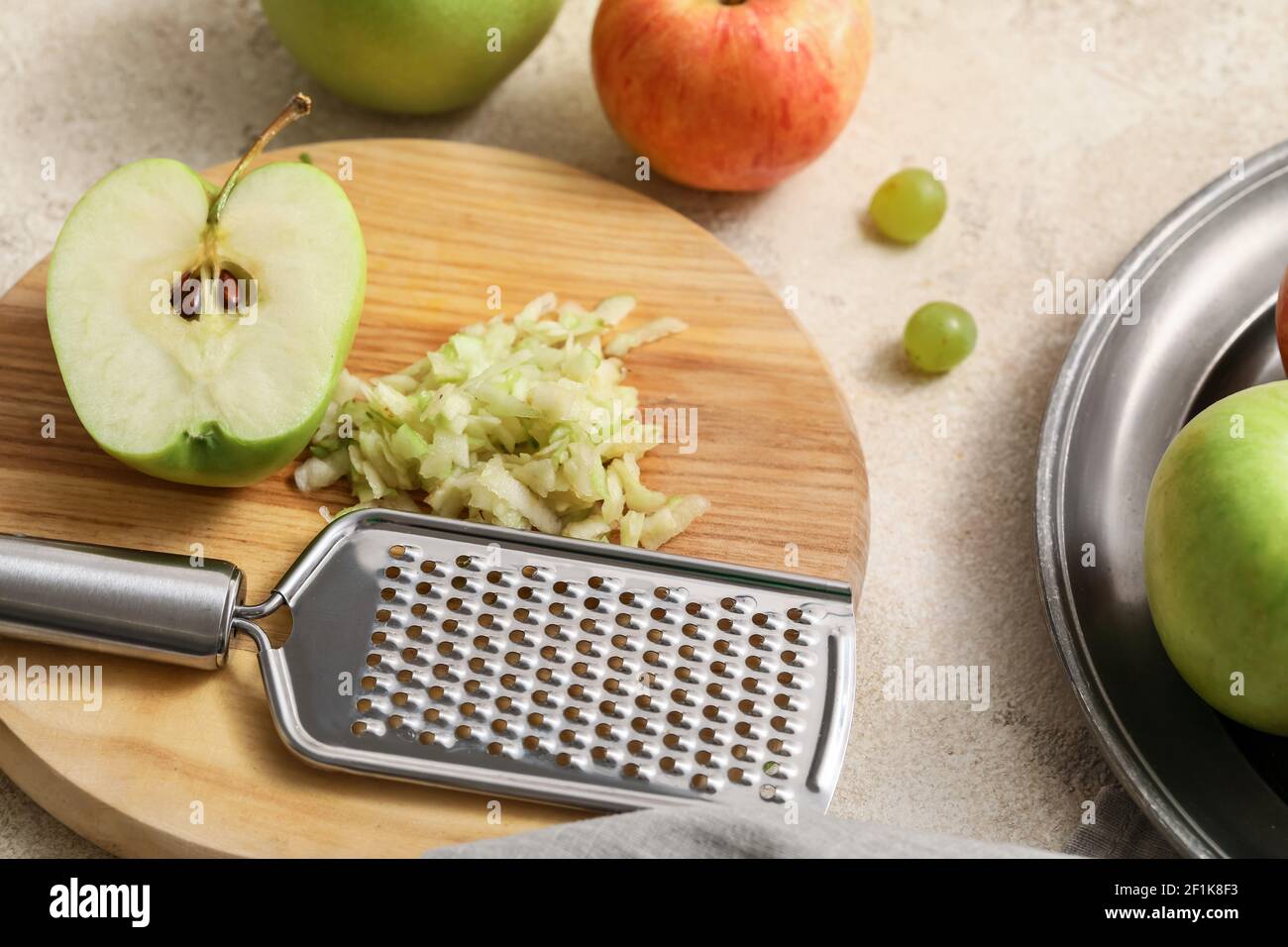 Metal grater and apples on light background Stock Photo - Alamy
