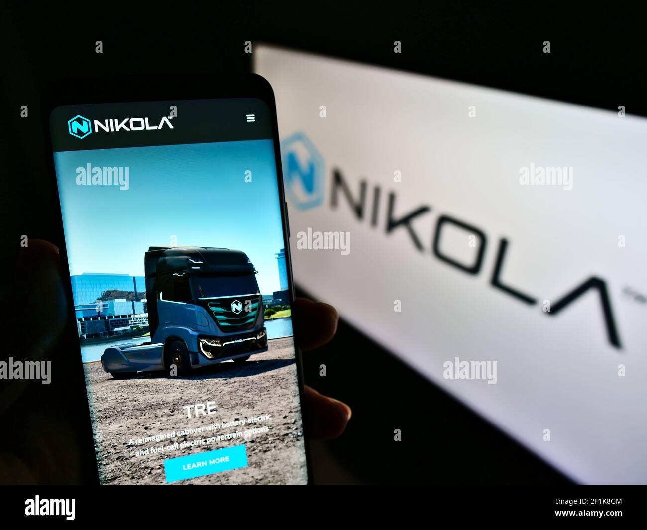Person holding mobile phone with web page of US electric vehicle ...