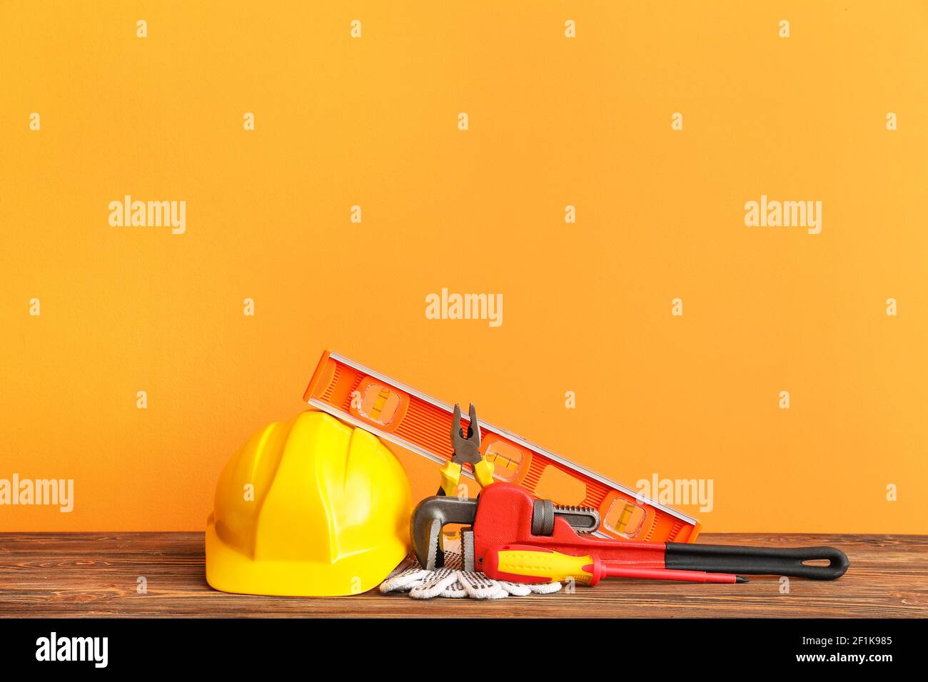 Set of construction tools on wooden table against color background ...