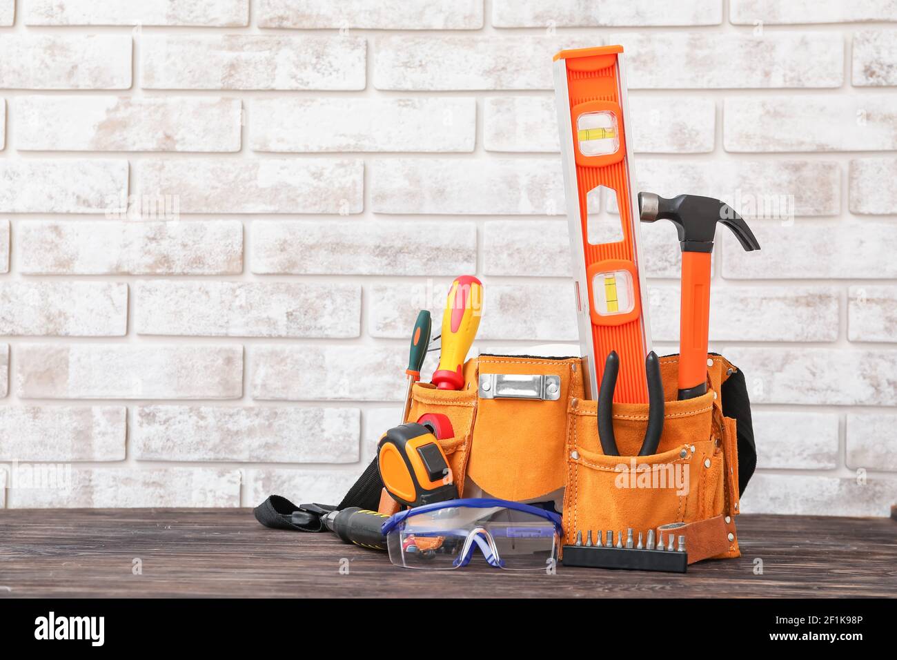 Set of construction tools on table against brick wall Stock Photo - Alamy