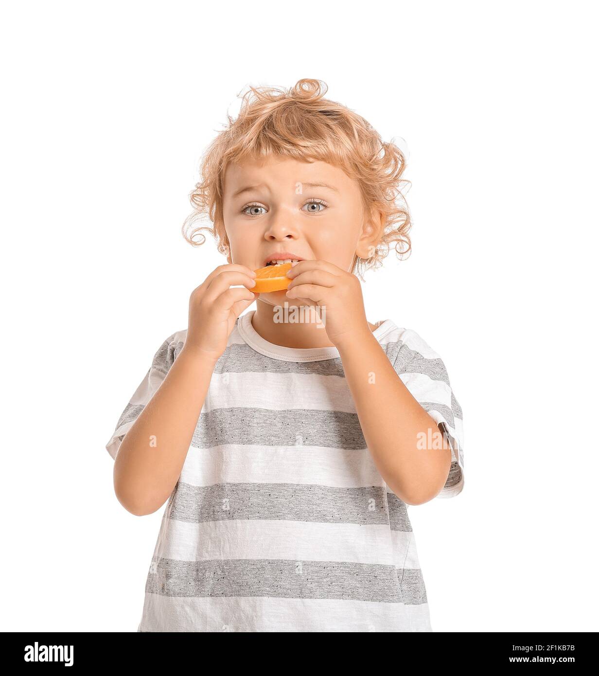 Cute little boy eating orange on white background Stock Photo - Alamy