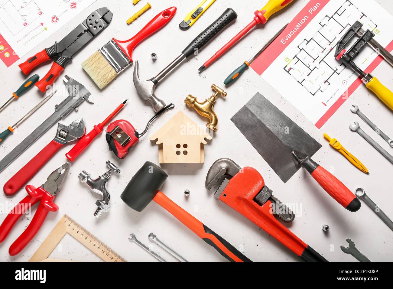 Composition with figure of house and construction tools on light ...