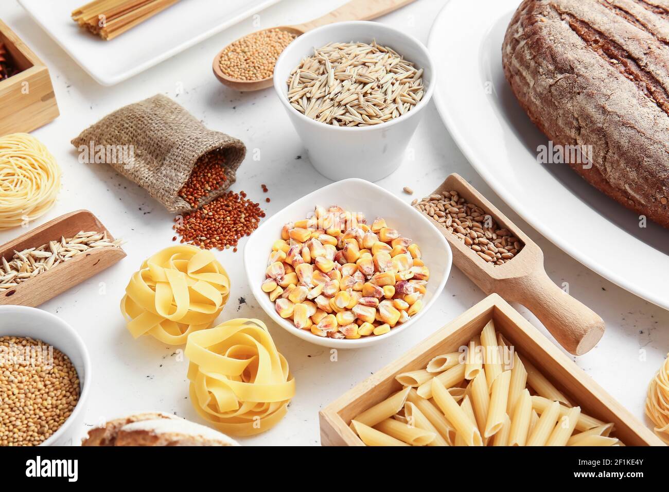 Different cereals, raw pasta and bread on light background Stock Photo ...