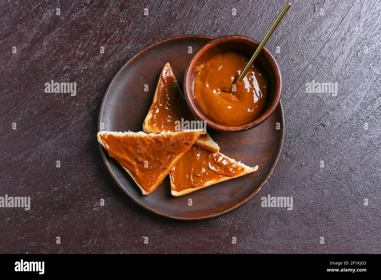 Tasty bread and boiled condensed milk on dark background Stock Photo ...