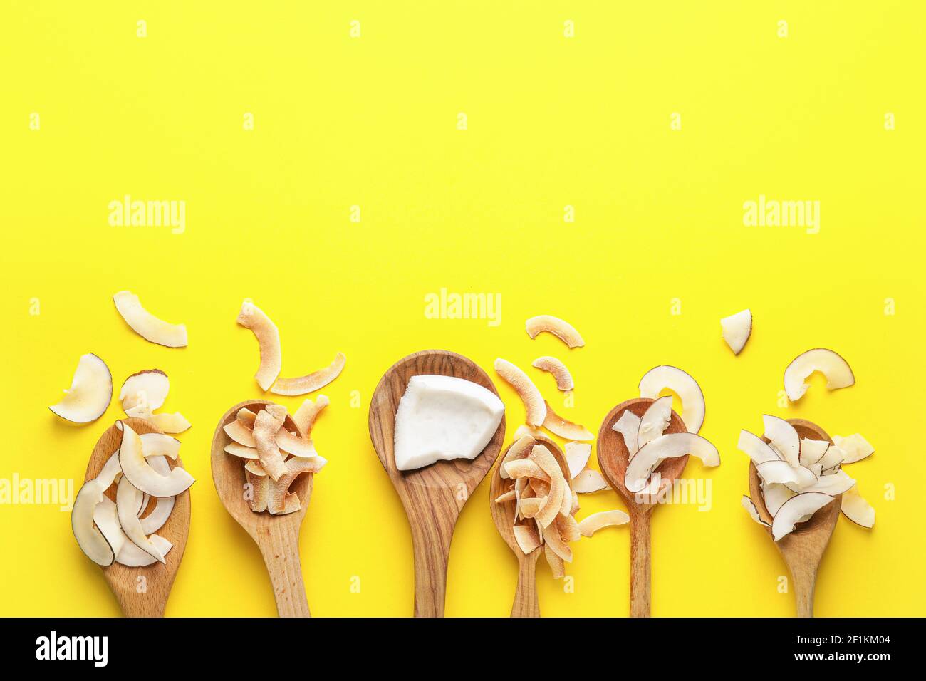 Spoons with tasty coconut chips on color background Stock Photo - Alamy