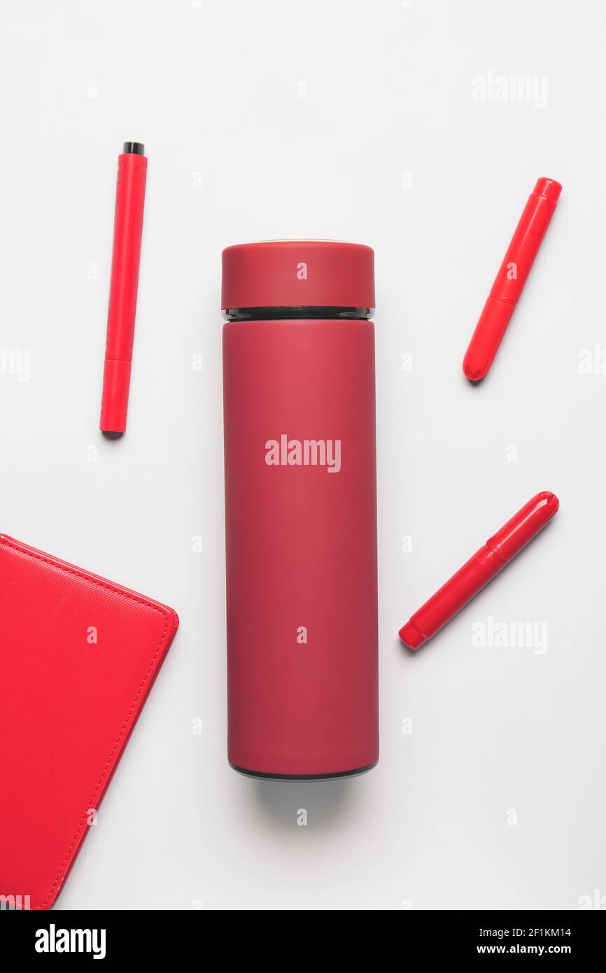 Modern thermos with notebook and pens on light background Stock Photo ...