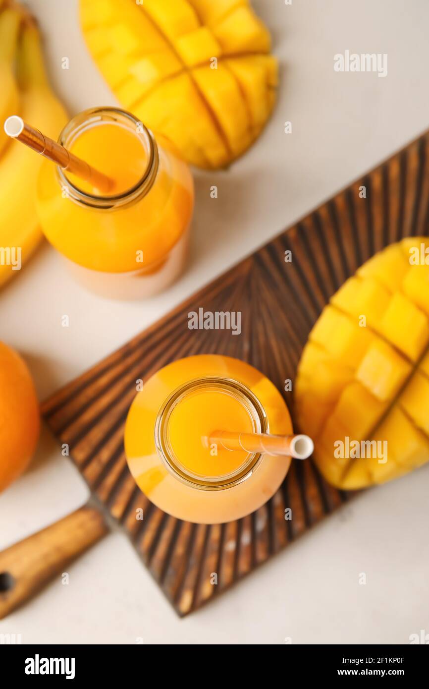 Bottles of fresh mango juice on light background Stock Photo - Alamy