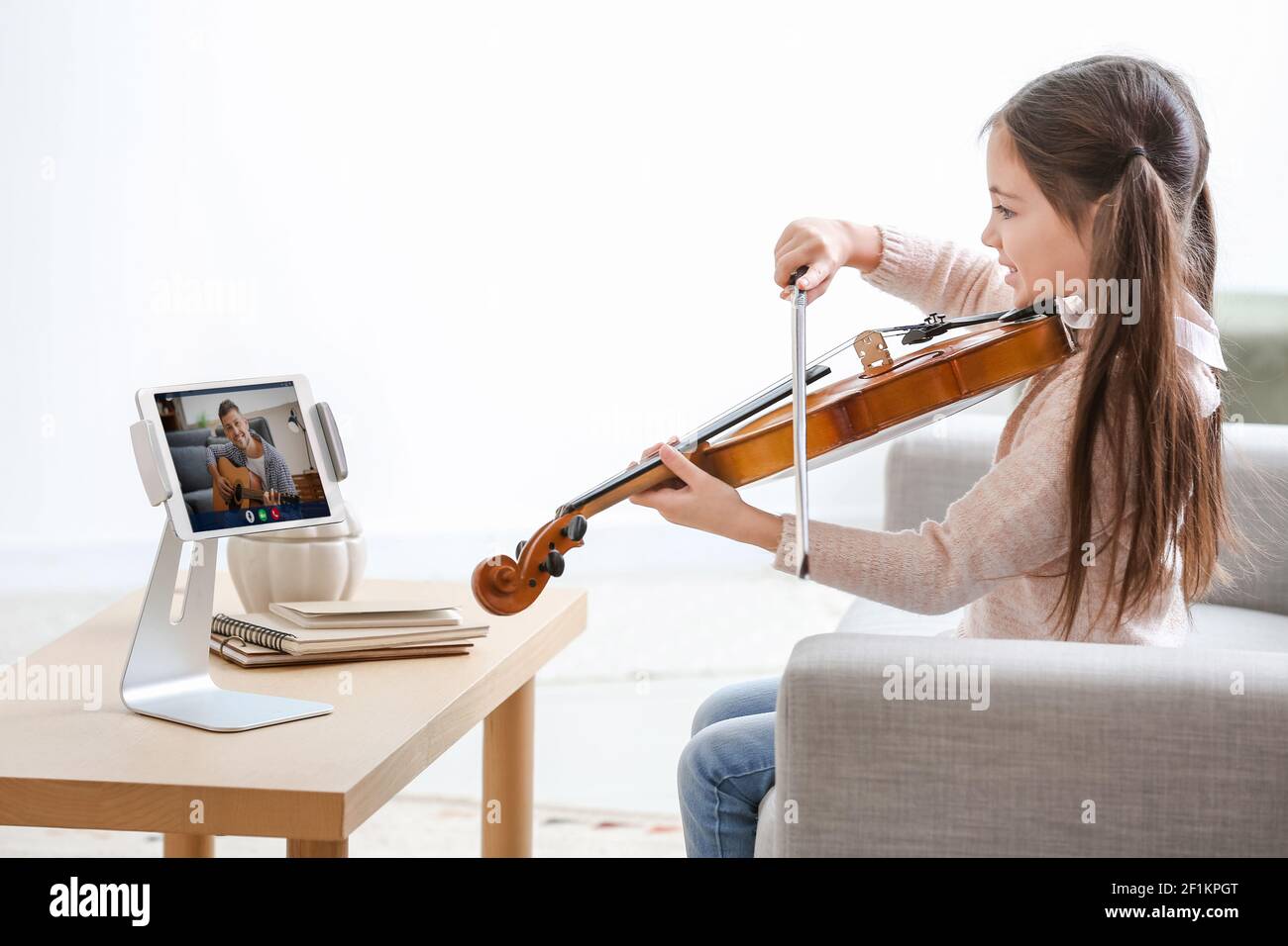 Little girl taking music lessons online at home Stock Photo - Alamy