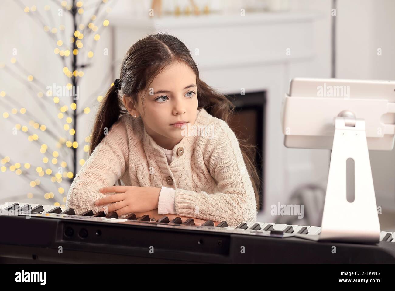 Bored little girl taking music lessons online at home Stock Photo - Alamy