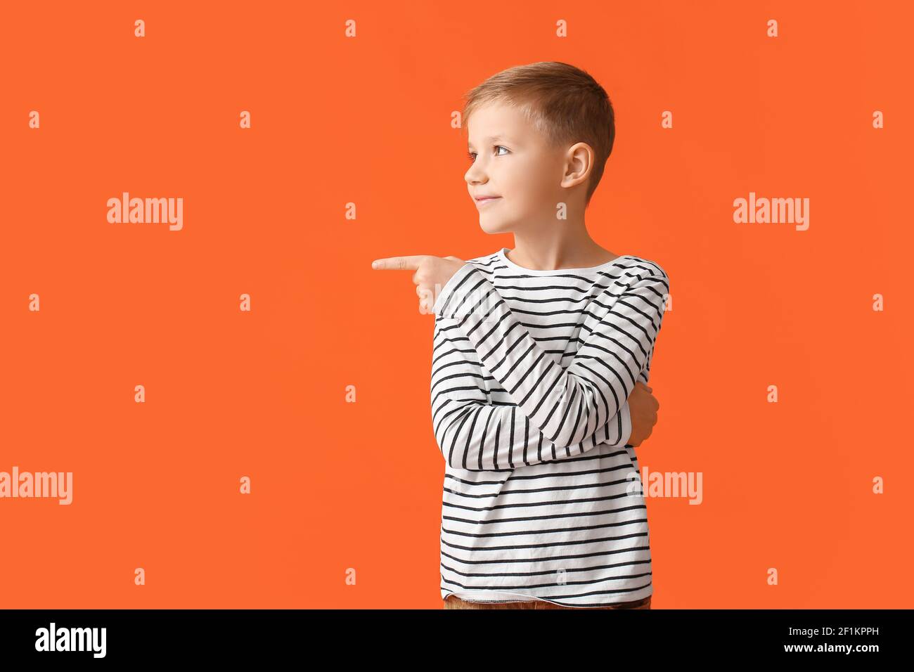 Cute little boy pointing at something on color background Stock Photo ...