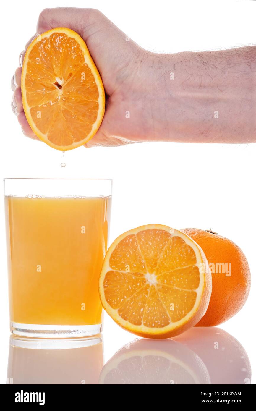 Hand squeezed fresh orange juice into a glass isolated on white ...