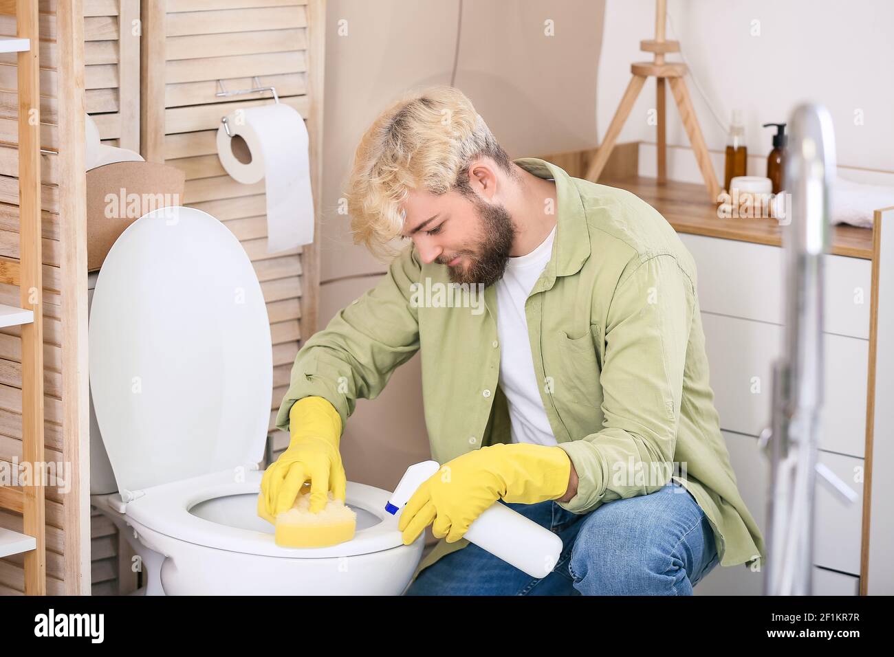 Young man cleaning toilet bowl in bathroom Stock Photo - Alamy