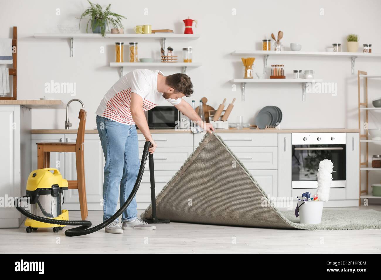 Young man hoovering floor in kitchen Stock Photo - Alamy