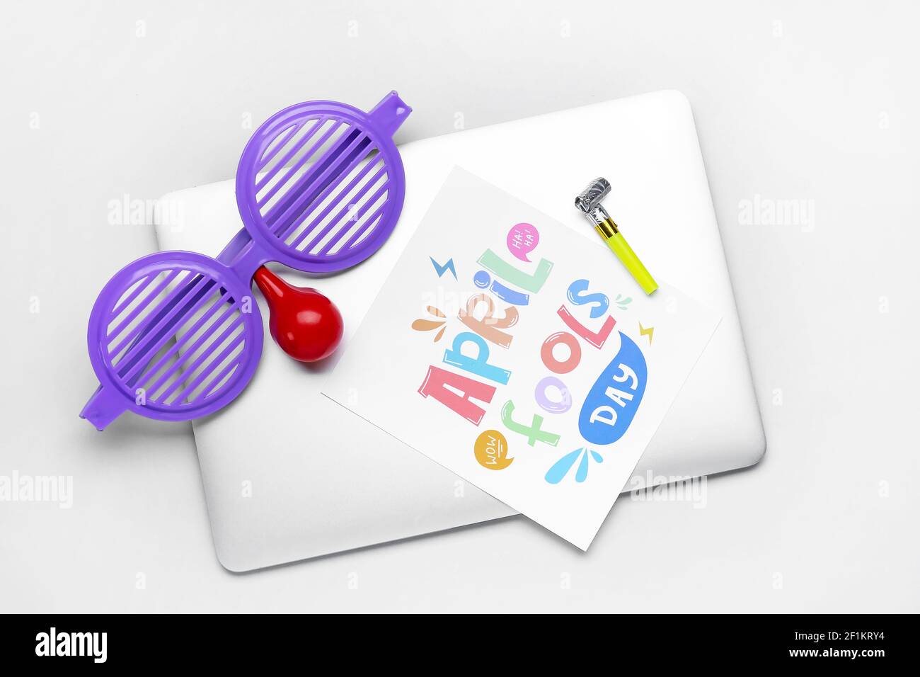 Laptop and party decor for April Fools Day celebration on grey ...