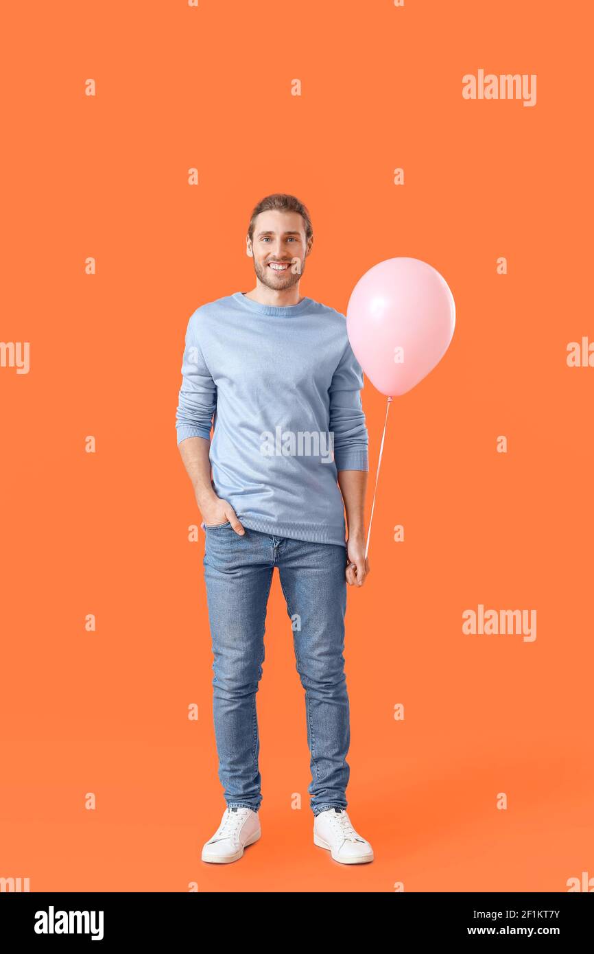 Handsome young man with balloon on color background Stock Photo - Alamy