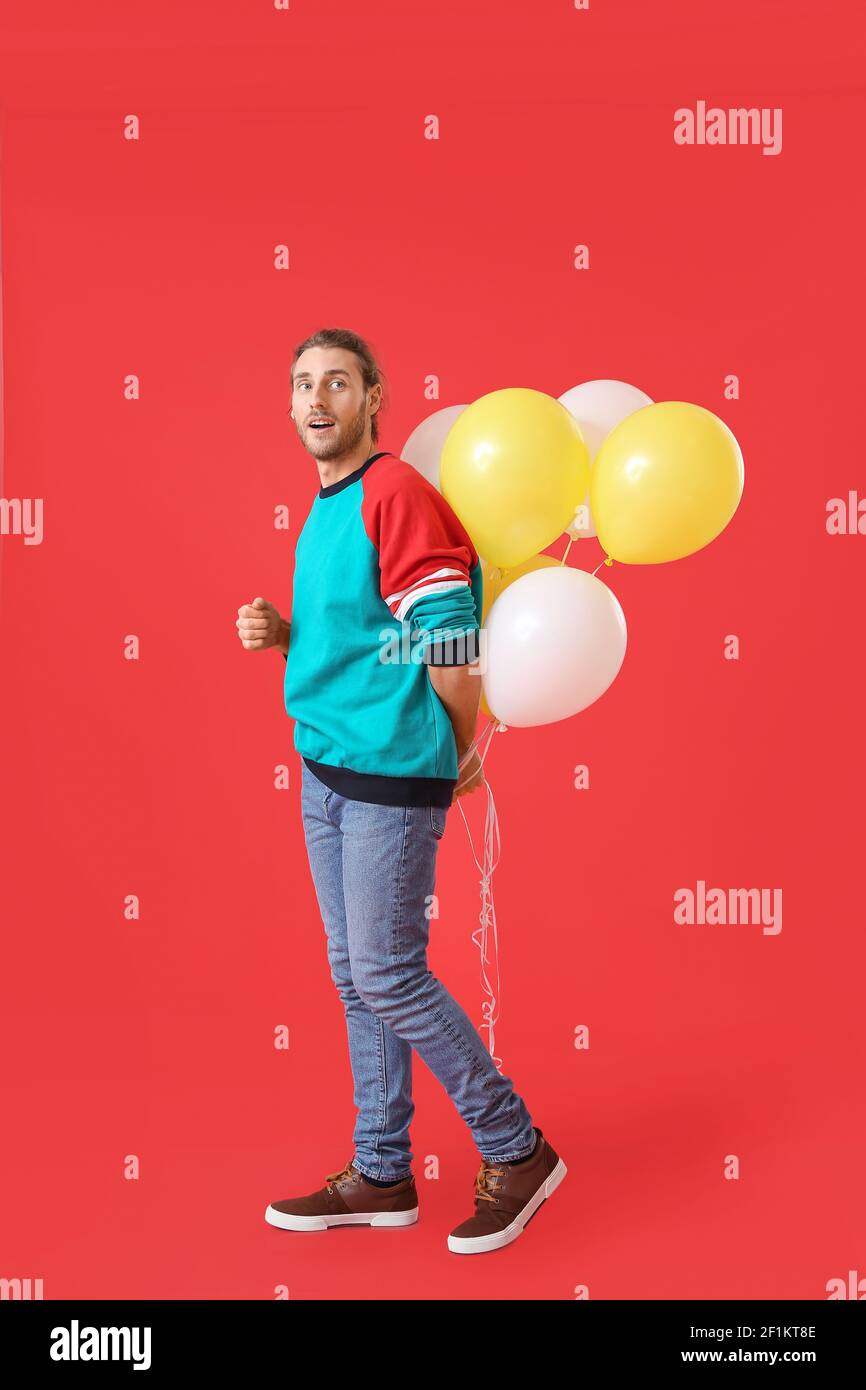 Handsome young man with balloons on color background Stock Photo - Alamy