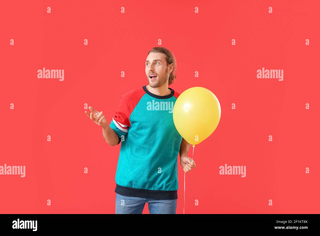 Handsome young man with balloon on color background Stock Photo - Alamy