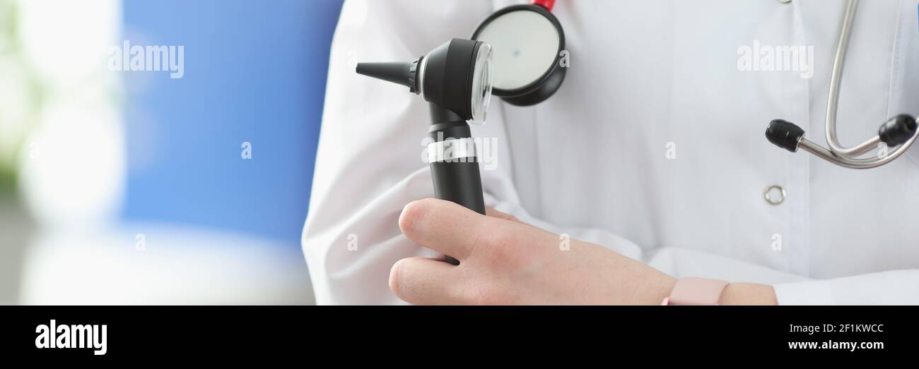 Otorhinolaryngologist holding otoscope in his hands in clinic closeup ...