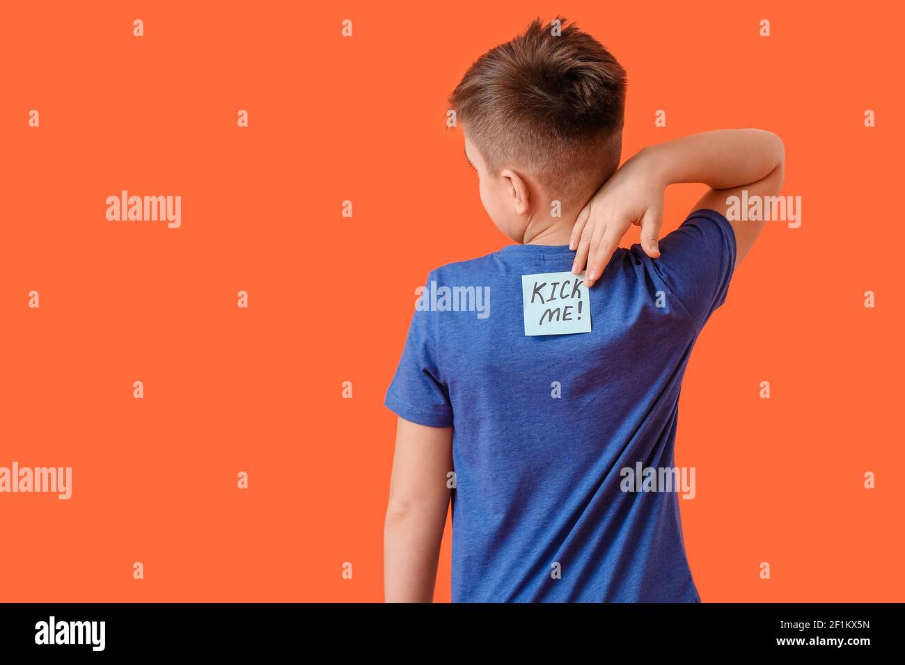 Sticky note with text KICK ME on back of little boy against color ...