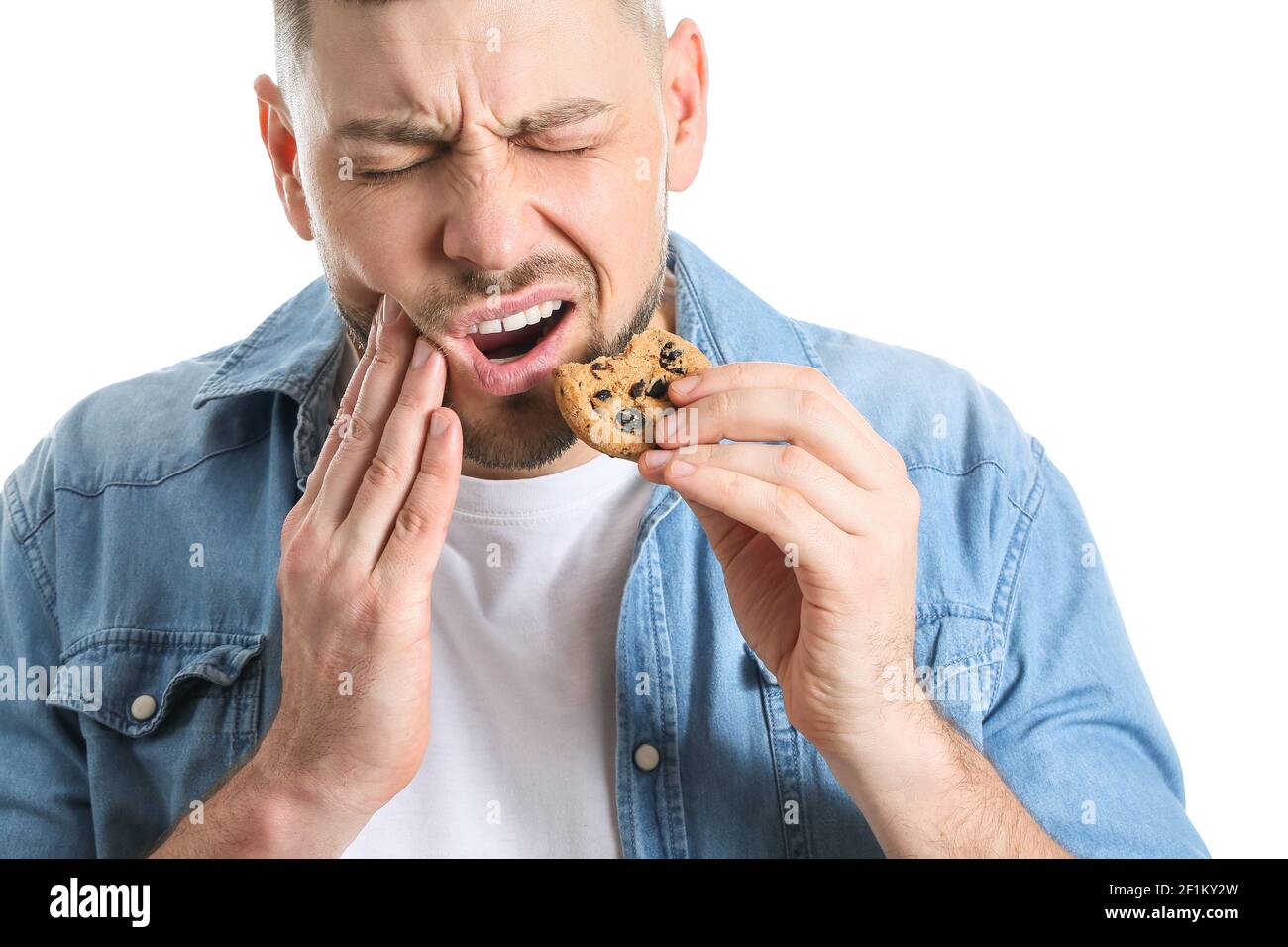 Man suffering from pain while eating cookie on white background Stock ...