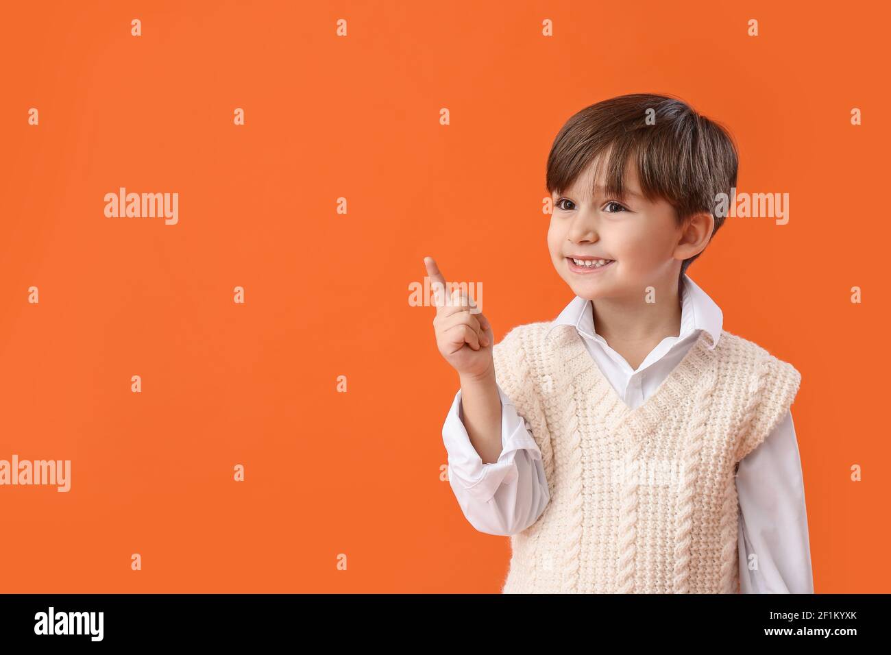 Cute little boy pointing at something on color background Stock Photo ...