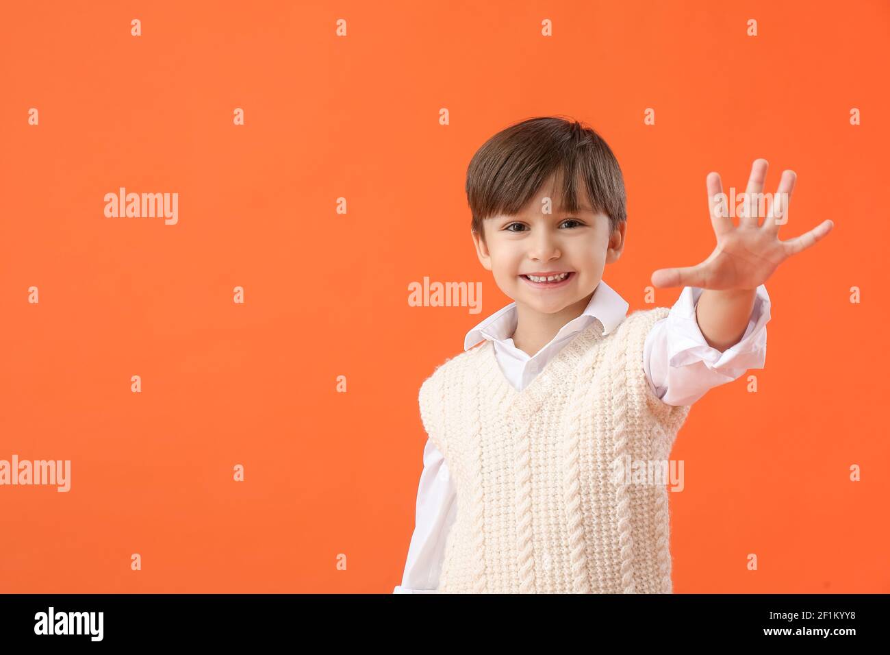 Cute little boy waving hand on color background Stock Photo - Alamy