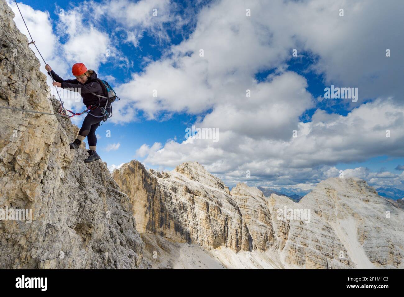 Female mountain climber on a steep Via Ferrata in the Italian Dolomites ...