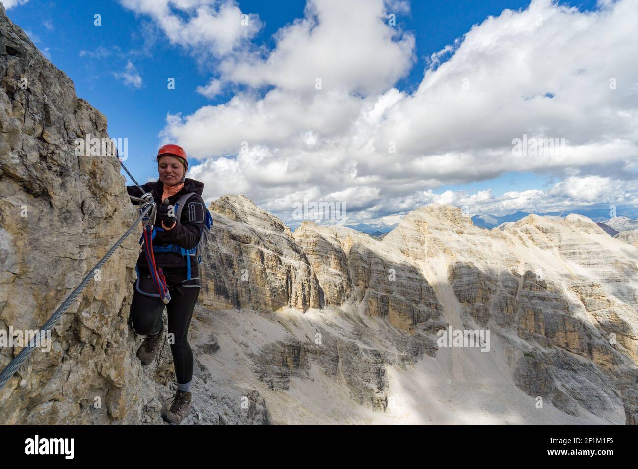Attractive blonde female mountain climber on a steep Via Ferrata in the ...