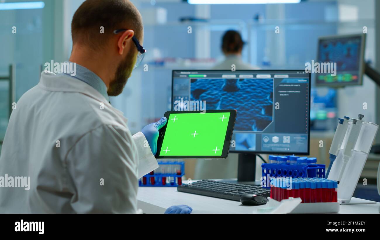 Researcher holding and looking at tablet with chroma key display in ...