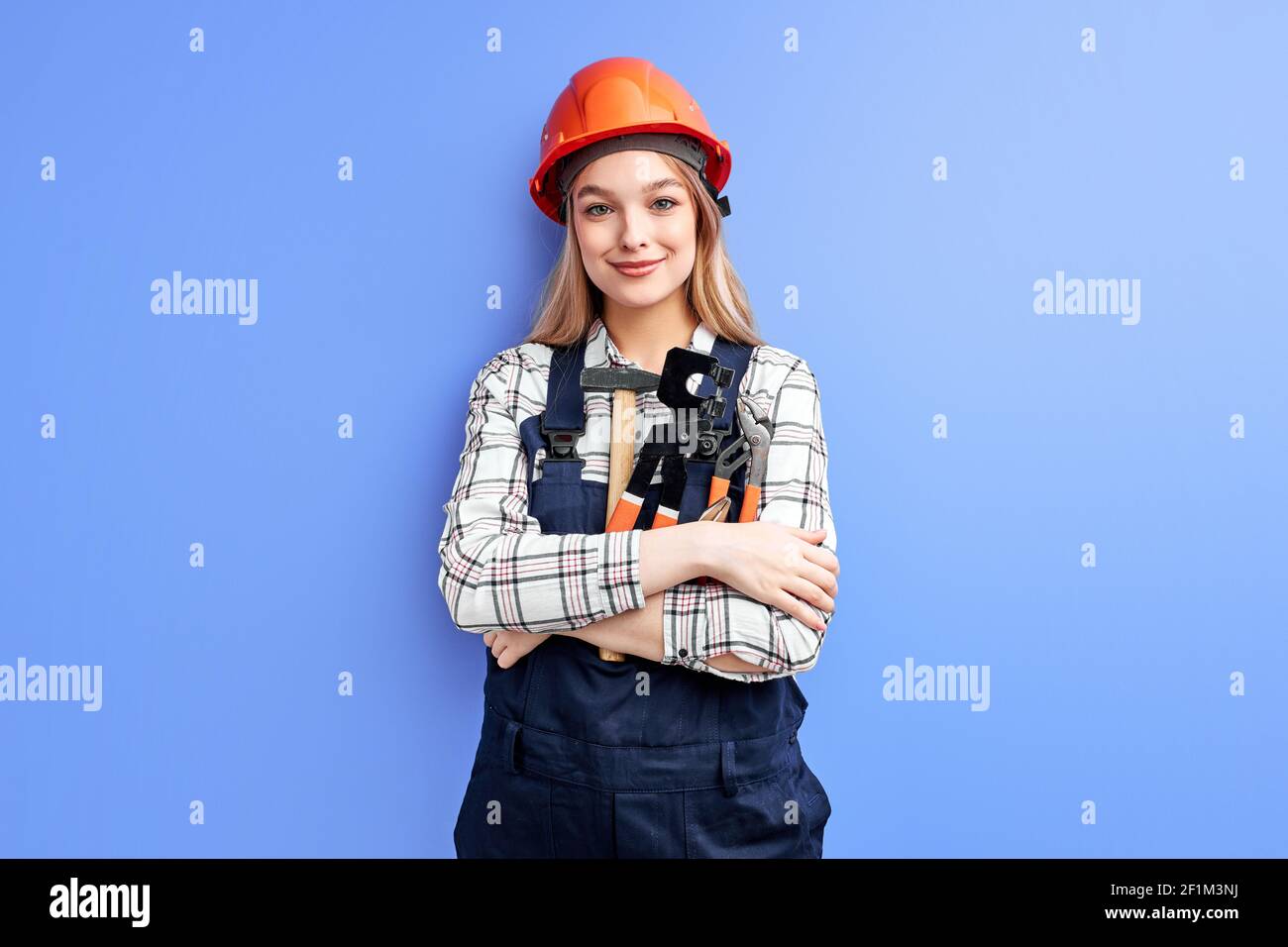 architect business woman in orange helmet standing against blue wall ...
