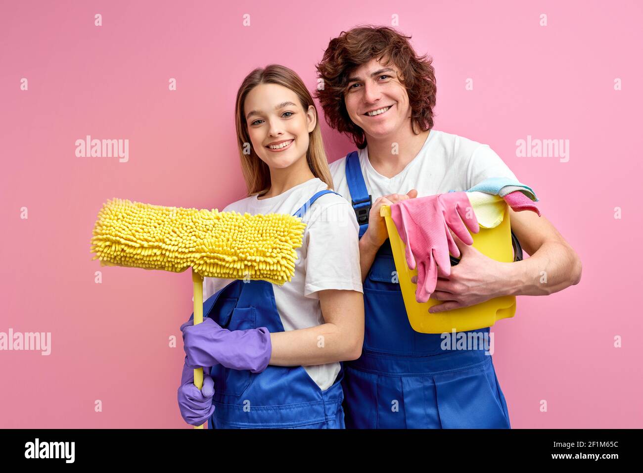 optimistic couple use rags and other tools for cleaning, posing at ...