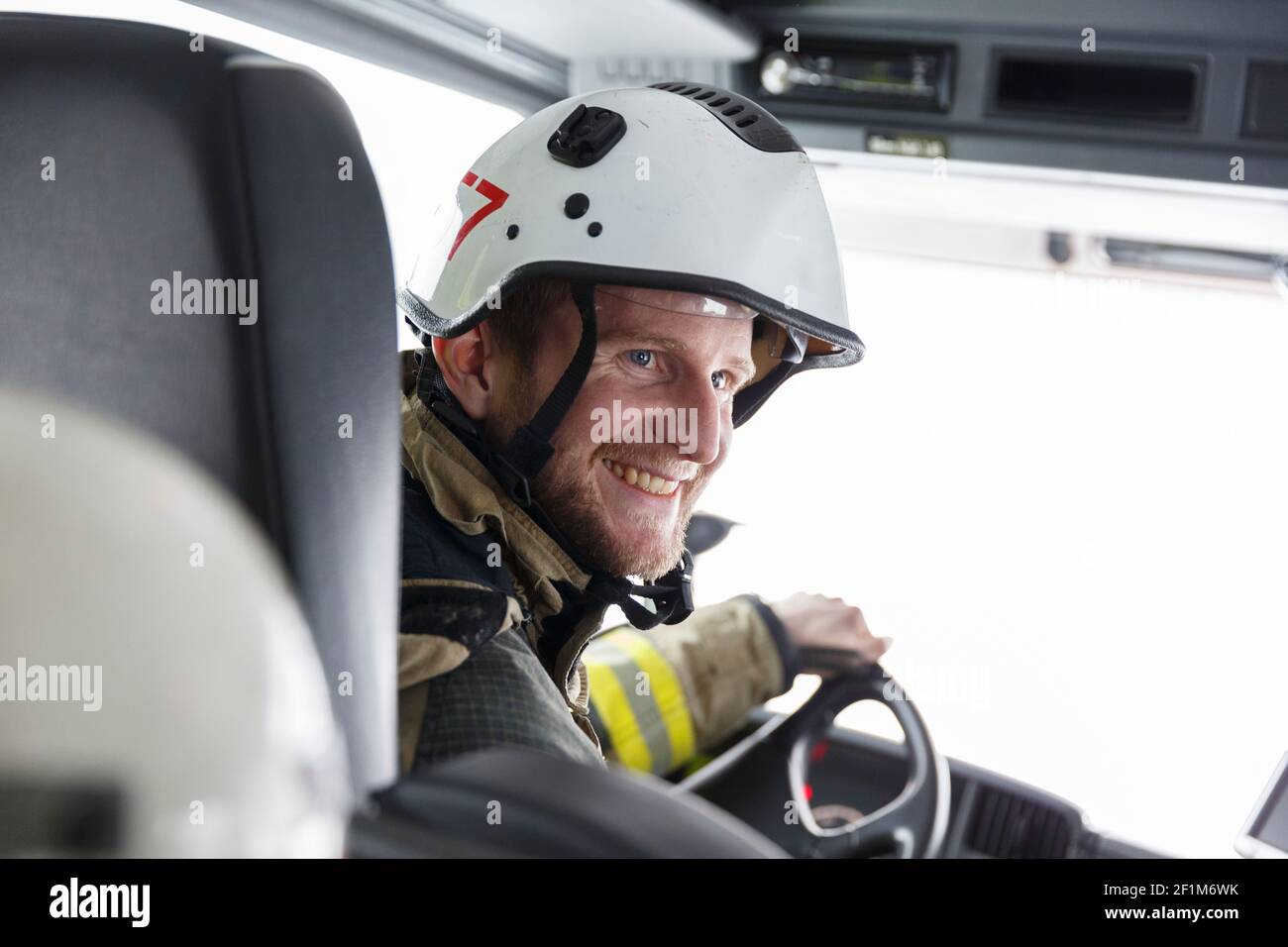 Smiling firefighter driving fire engine Stock Photo - Alamy