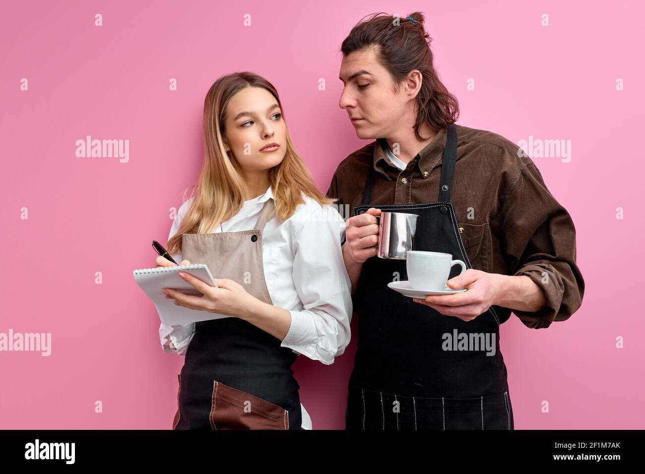 two young waiters in apron discuss orders, ready to serve clients ...